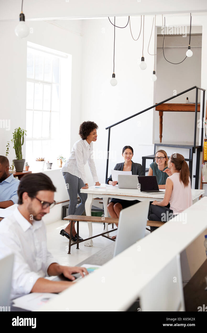 Woman briefing colleagues in an open plan office, vertical Stock Photo ...