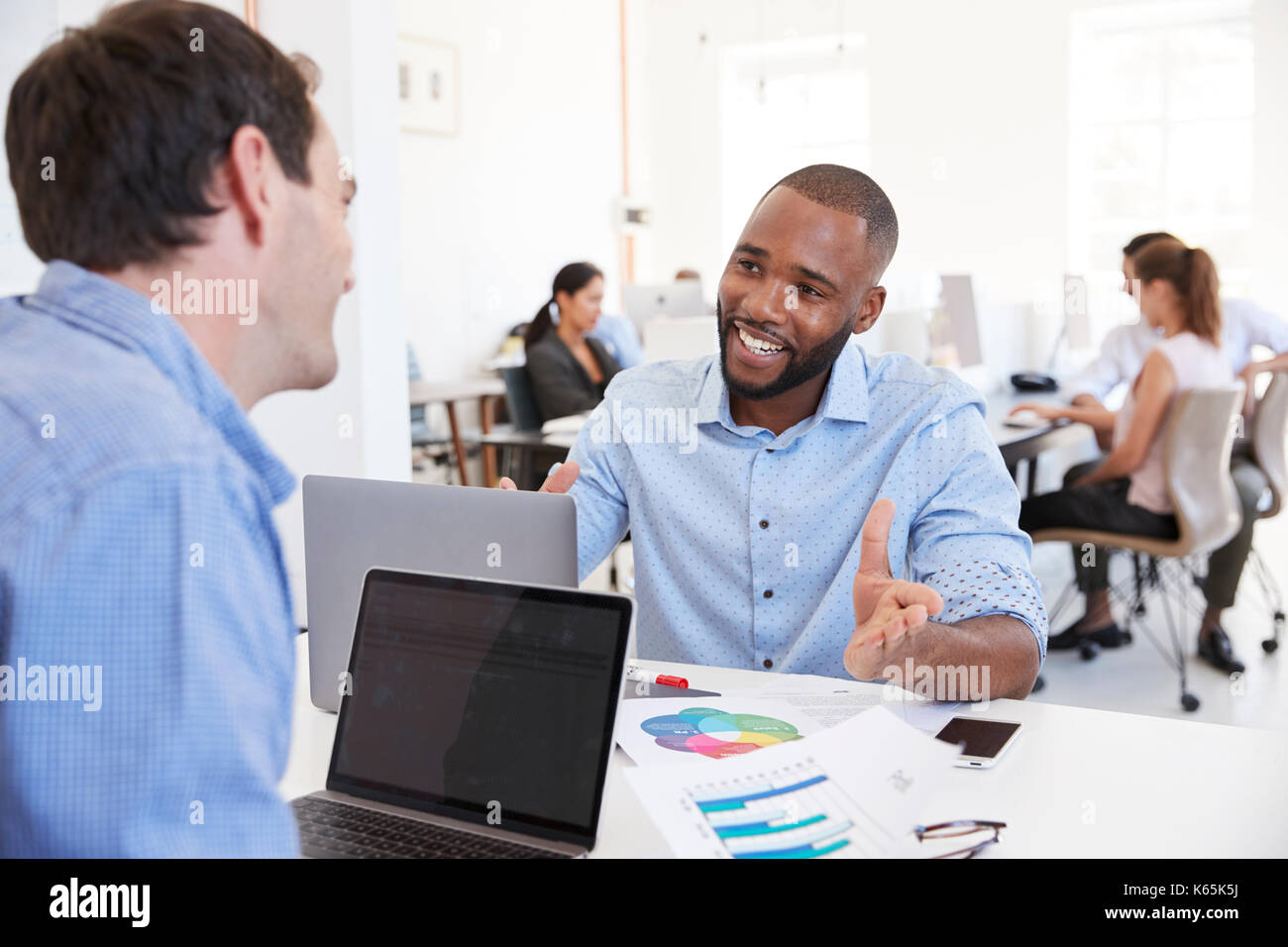 Two men discussing business in a busy office Stock Photo - Alamy