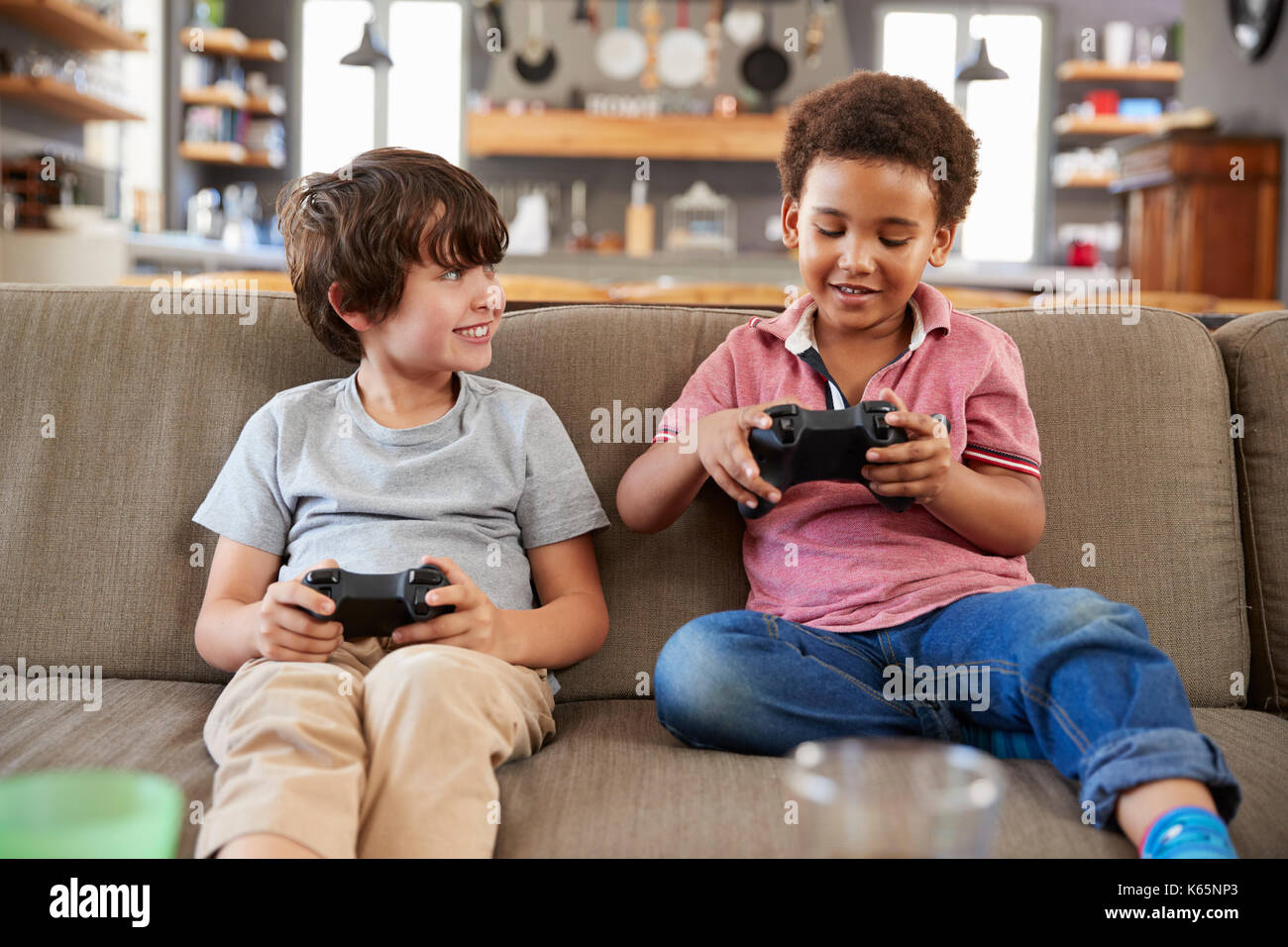 Two Boys Sitting On Sofa In Lounge Playing Video Game Together Stock ...