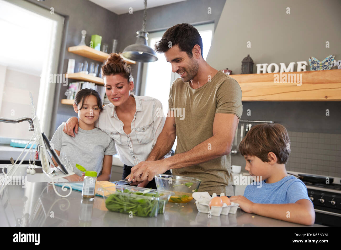 Family In Kitchen Following Recipe On Digital Tablet Together Stock ...
