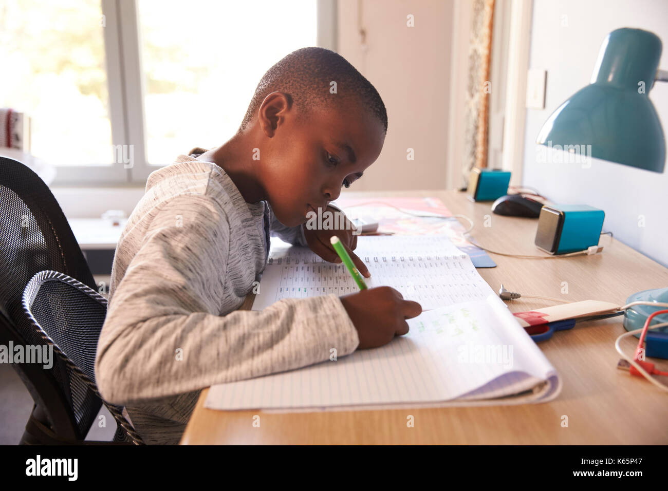 Young Boy In Bedroom Sitting At Desk Doing Homework Stock Photo - Alamy