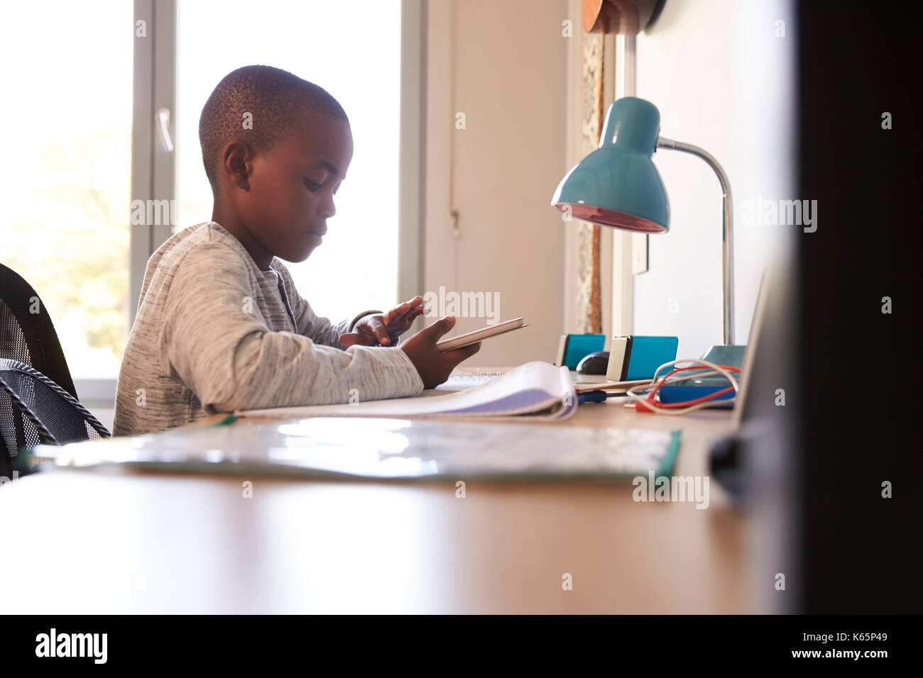 Boy In Bedroom Using Digital Tablet To Do Homework Stock Photo - Alamy