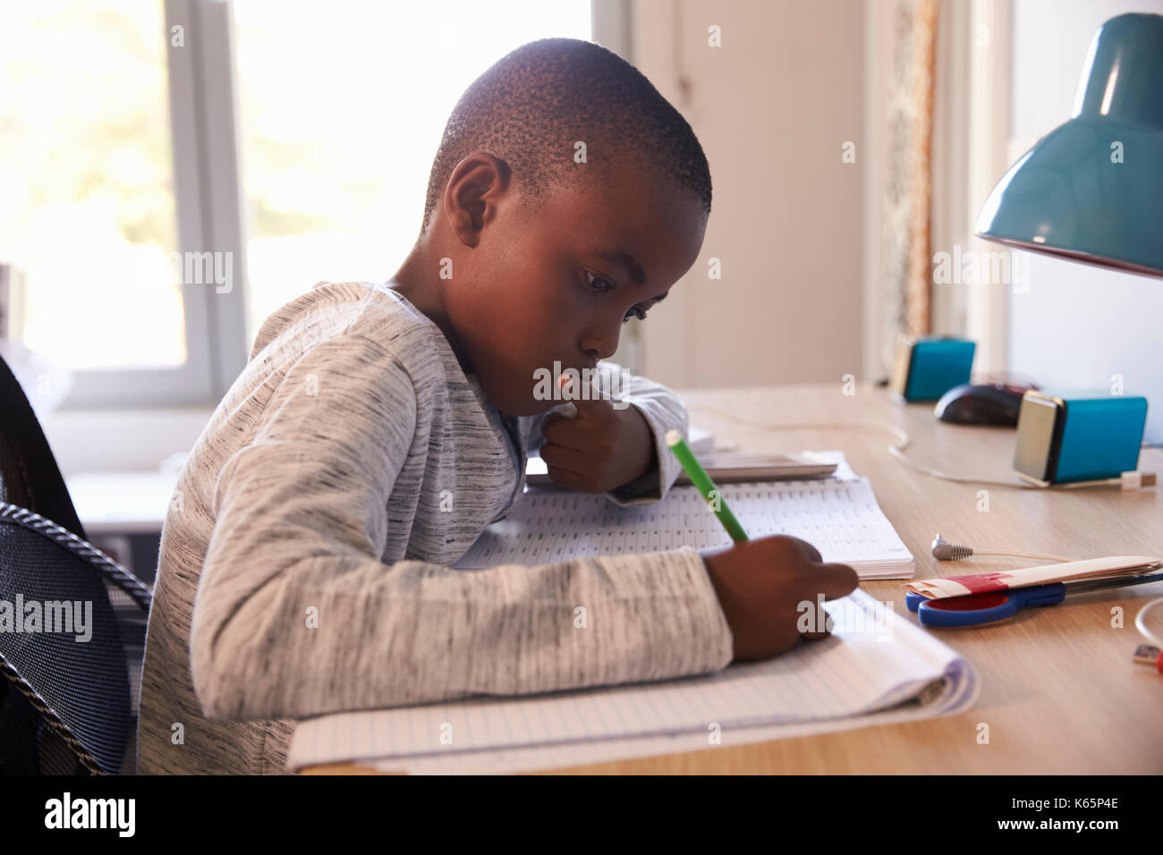 Young Boy In Bedroom Sitting At Desk Doing Homework Stock Photo - Alamy