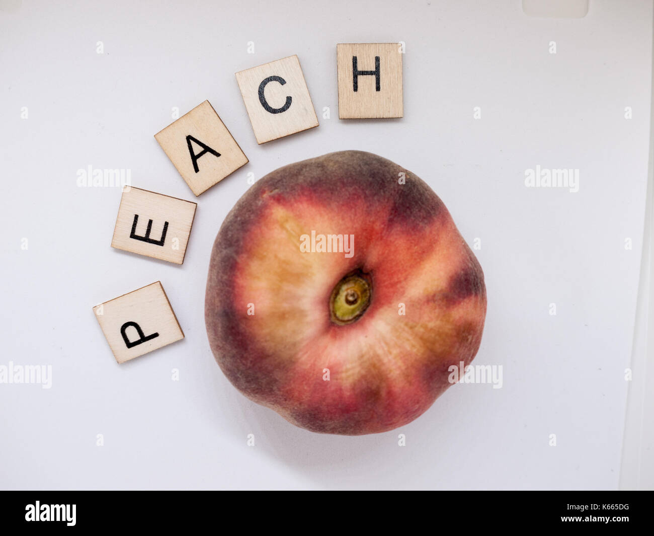 The word "Peach" arranged in wooden letter tiles around a peach Stock ...