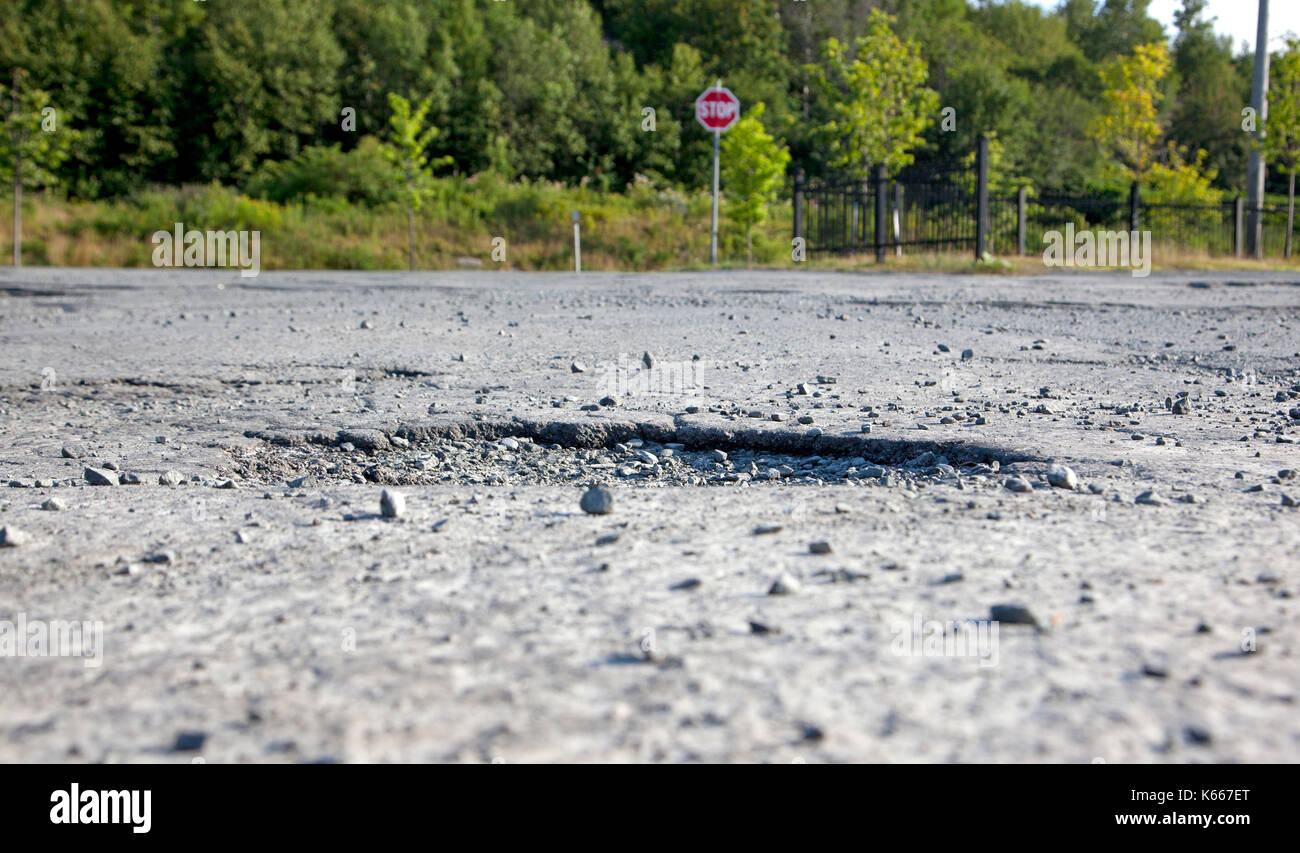 large gaping pothole in the road with stop sign in background Stock ...