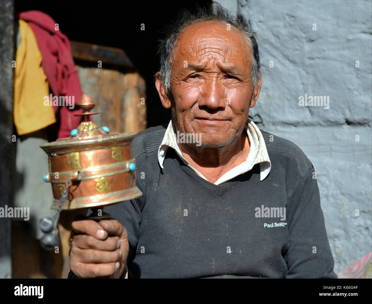 Old Nepali Gurung man swings a Tibetan hand prayer wheel (mani wheel ...