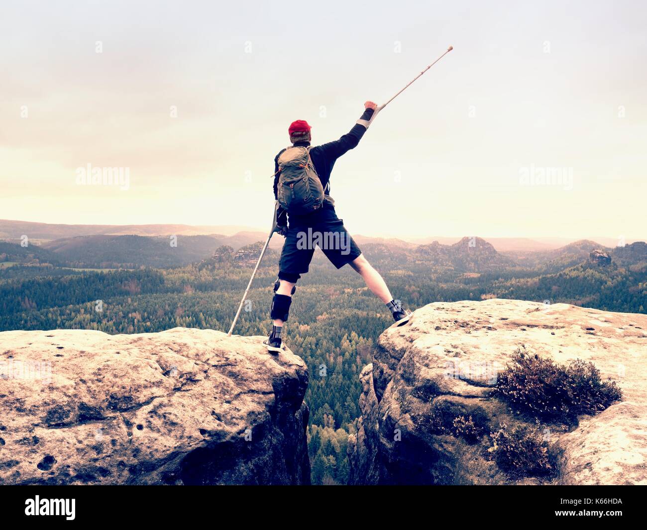 Peak triumph. Man with leg in knee cages and crutches for stabilization ...