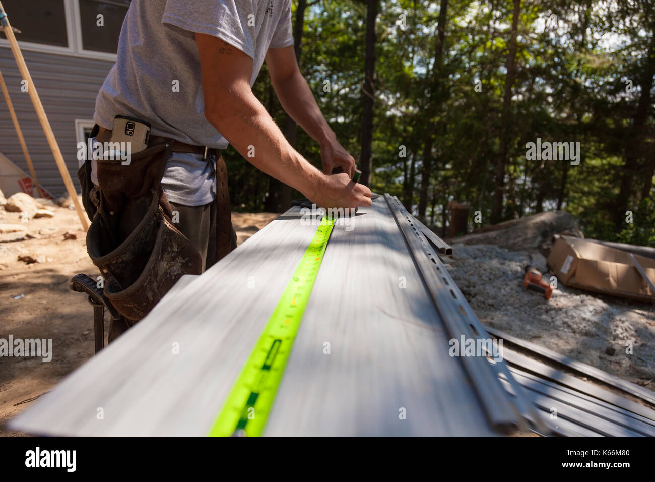 A construction worker marking vinyl siding using a pencil and a tape ...