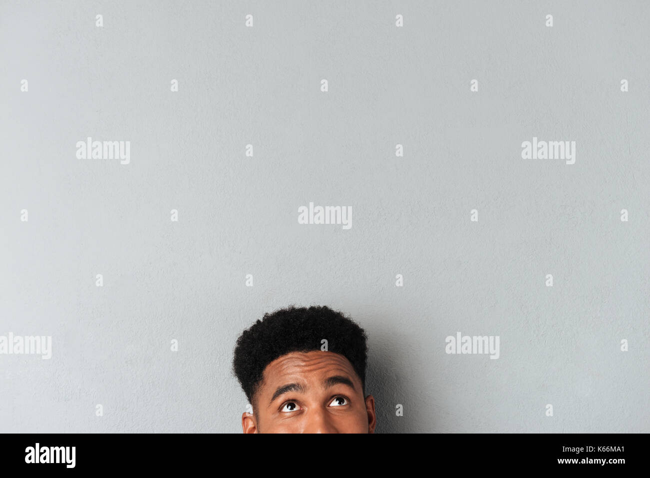 Half face of an african man looking up at copy space isolated over gray ...