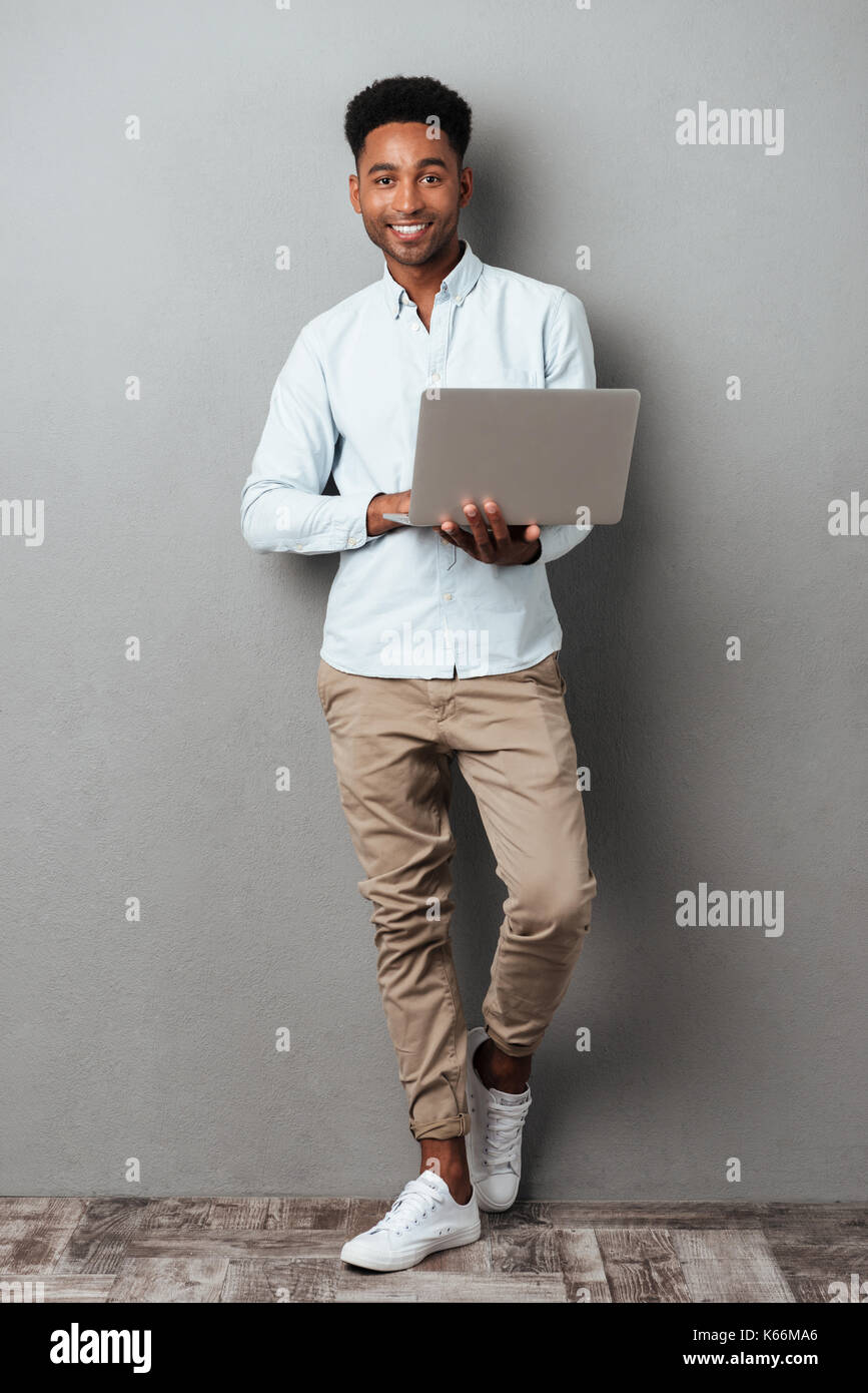 Full length portrait of a young smiling african man standing and ...