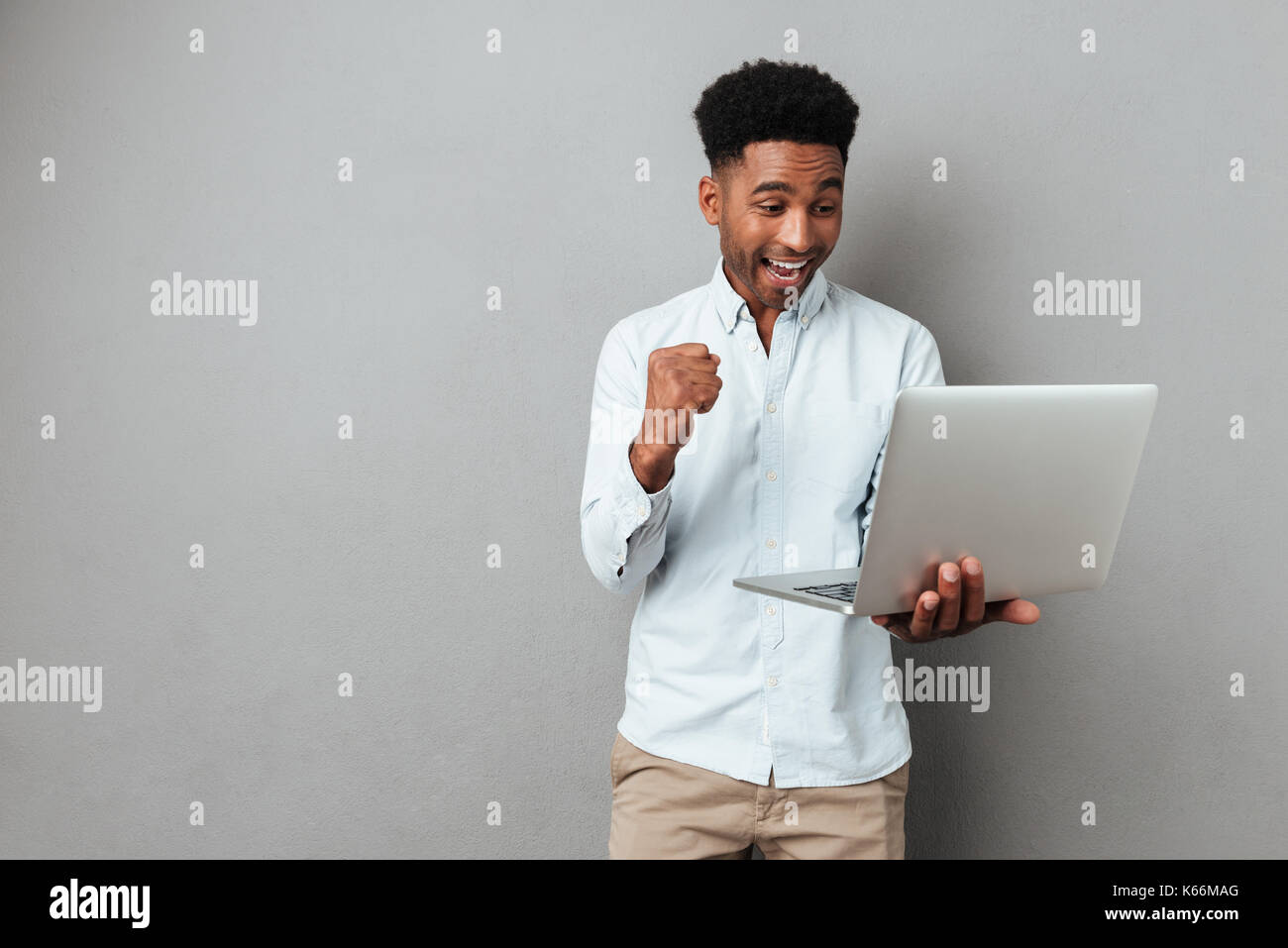 Excited happy afro american man looking at laptop computer screen and ...