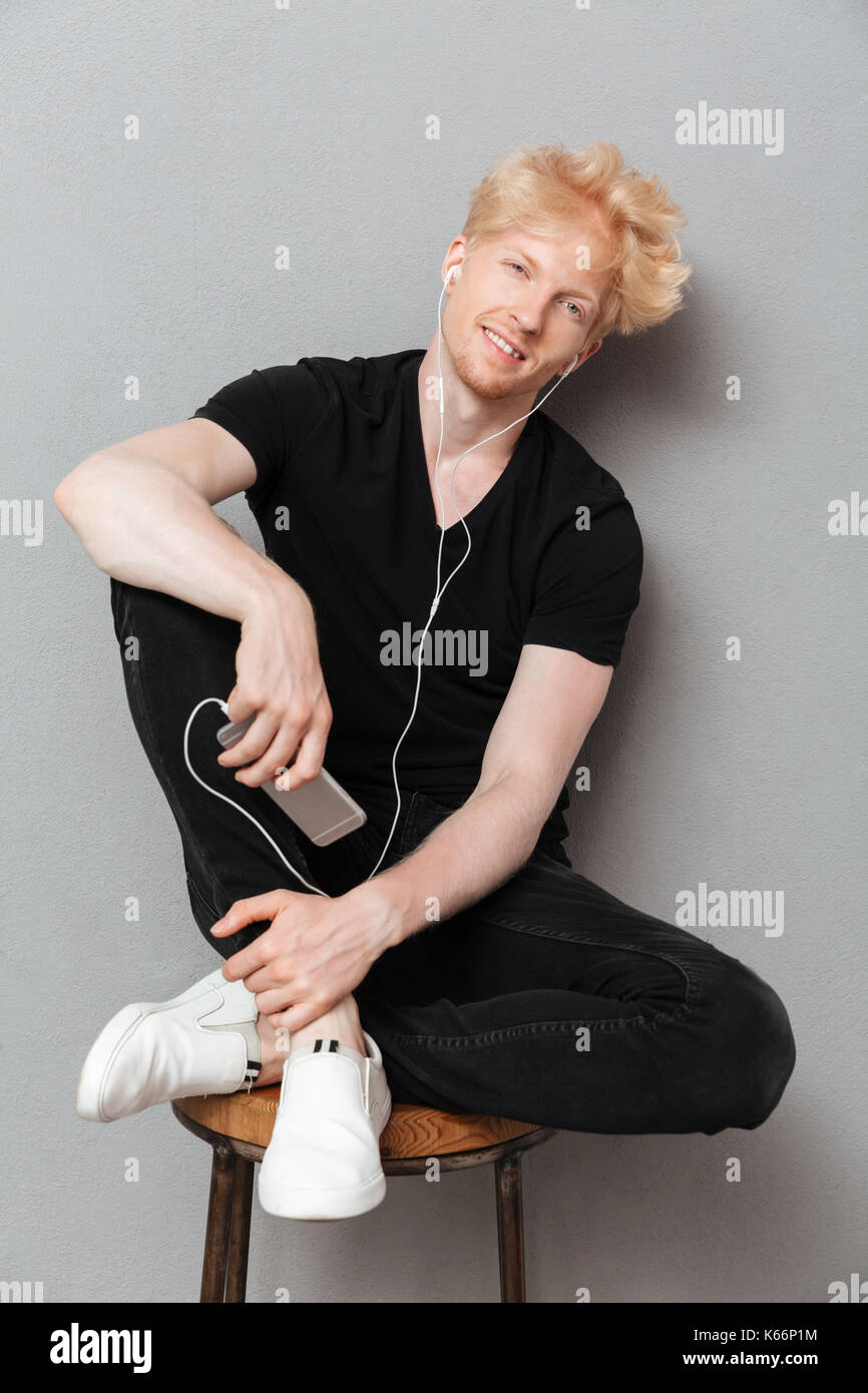 Image of cheerful caucasian man over grey wall near copyspace listening ...