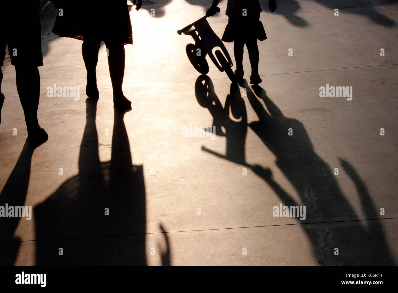 Blurry shadows of a family with little girl pushing a small bike on ...