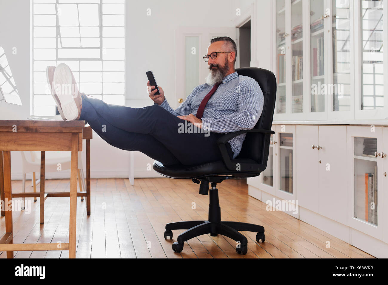 Caucasian man with feet up texting on cell phone Stock Photo - Alamy