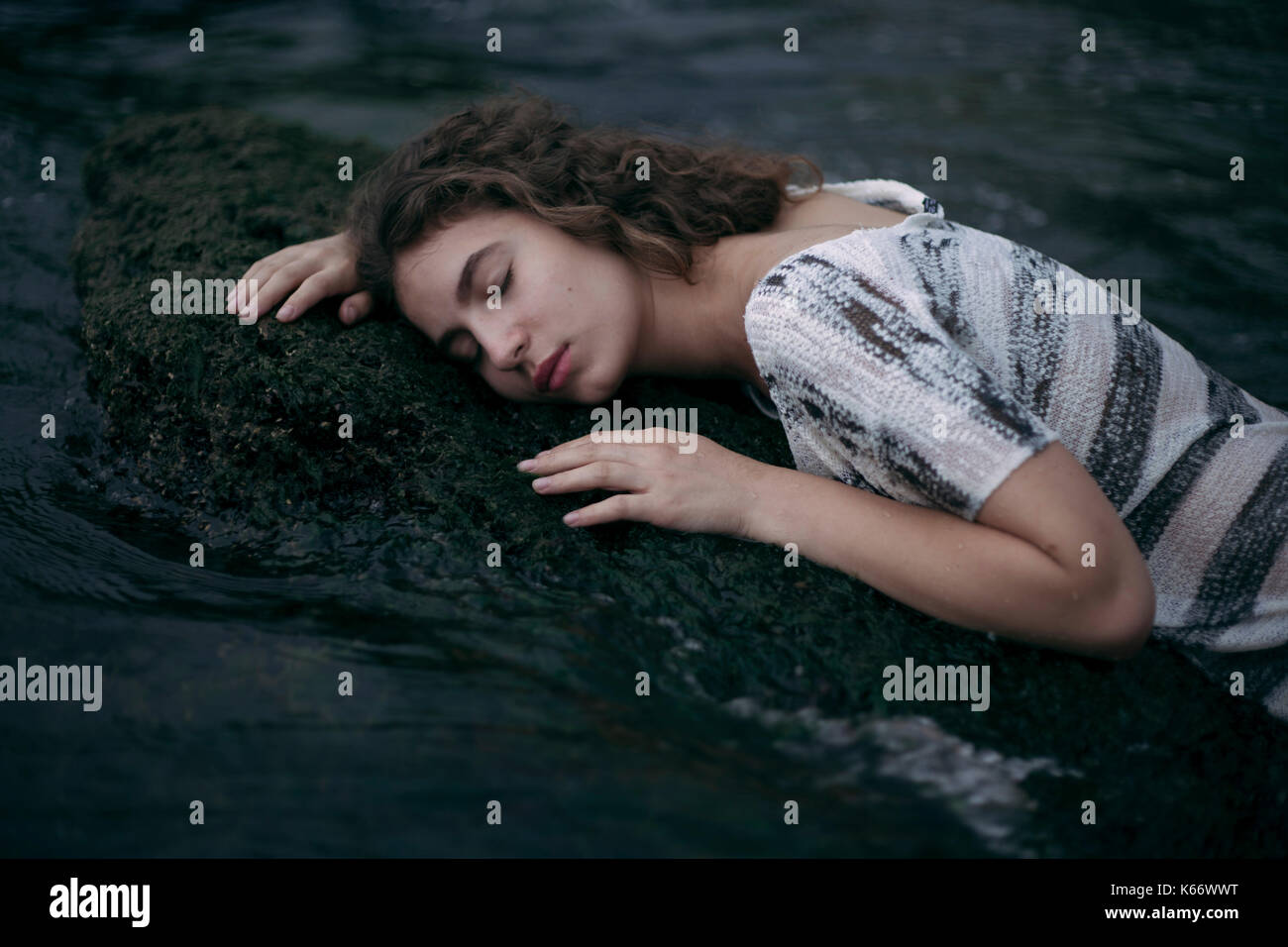 Caucasian girl laying face on a rock in ocean Stock Photo - Alamy
