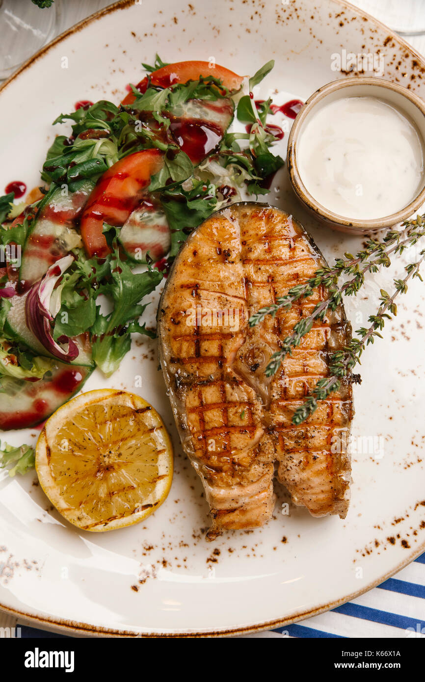 Grilled fish and salad on plate with sauce Stock Photo - Alamy