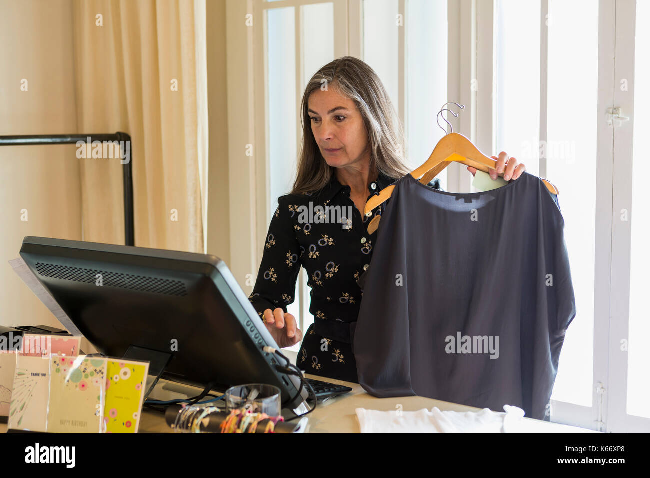 Caucasian woman holding clothing using computer Stock Photo - Alamy