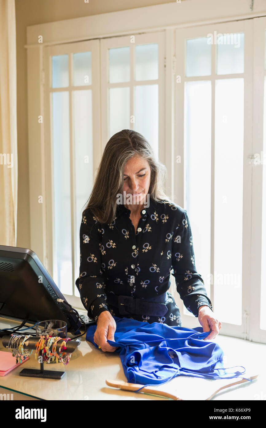 Caucasian woman holding clothing near computer Stock Photo - Alamy