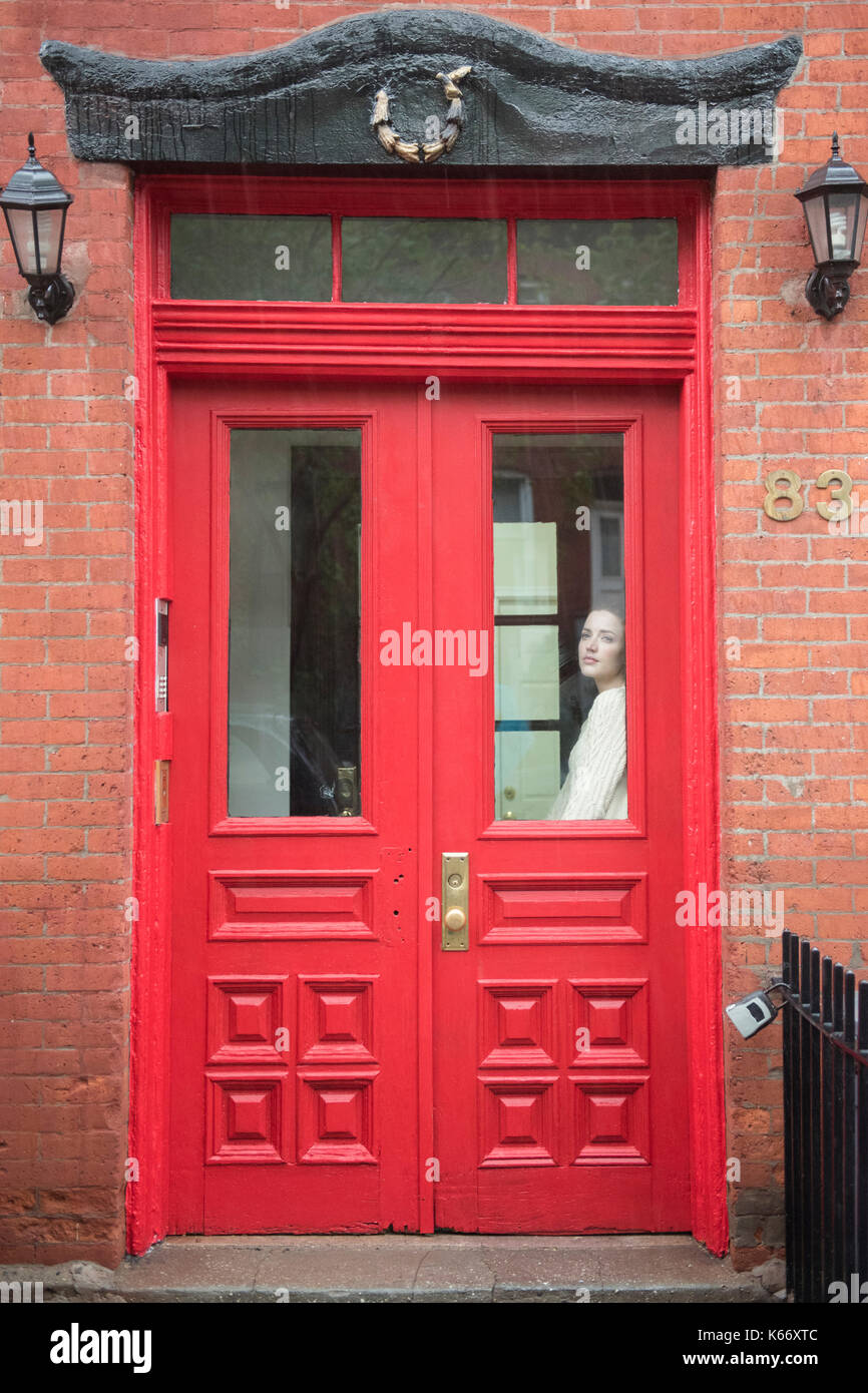 Caucasian woman daydreaming behind red door Stock Photo - Alamy