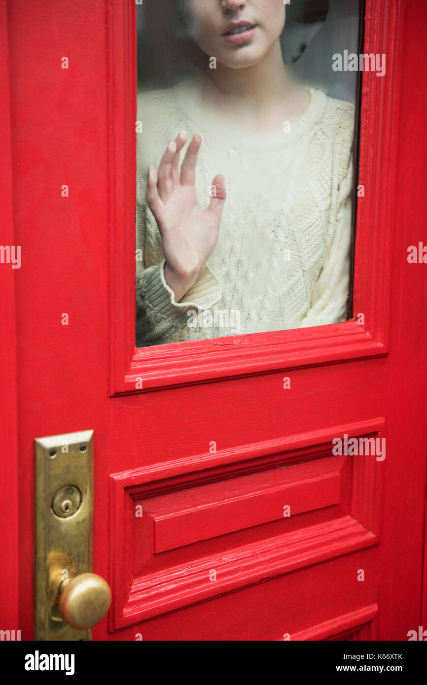 Caucasian woman daydreaming behind red door Stock Photo - Alamy
