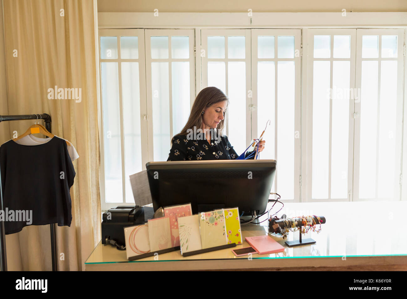 Caucasian woman using computer in clothing store Stock Photo - Alamy