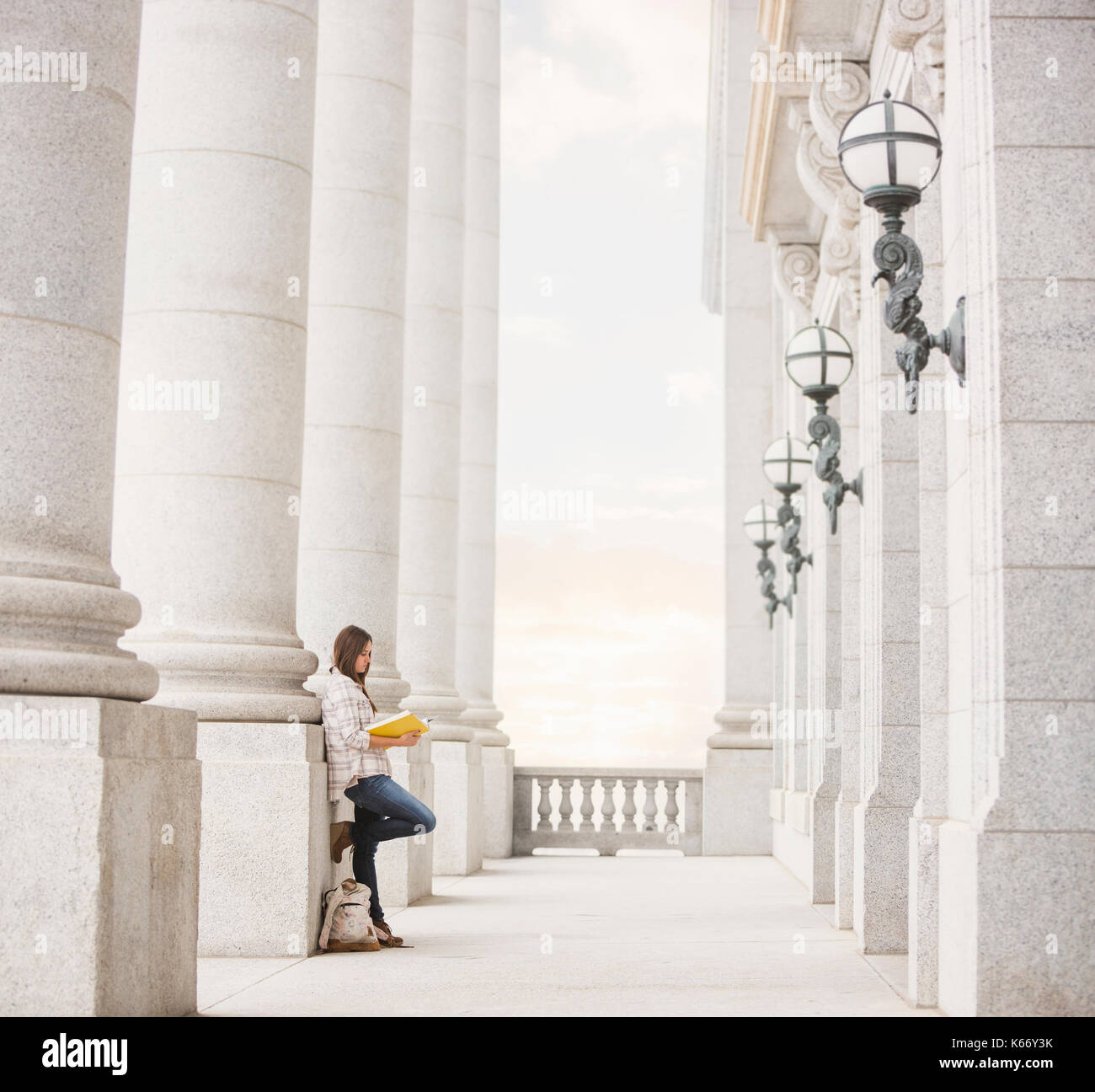 Caucasian woman leaning on pillar reading notebook Stock Photo - Alamy