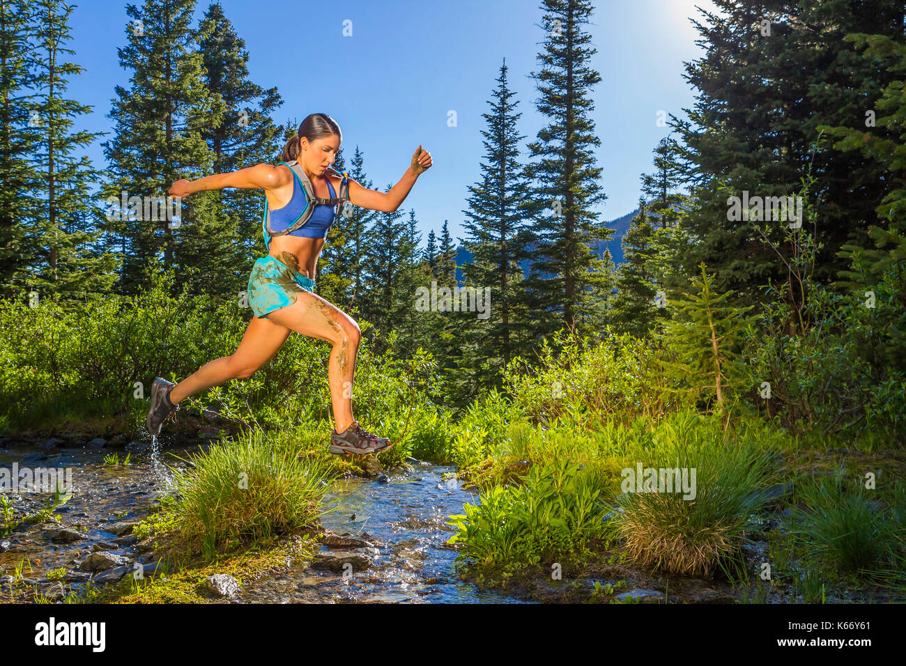 Hispanic woman jumping over stream Stock Photo - Alamy