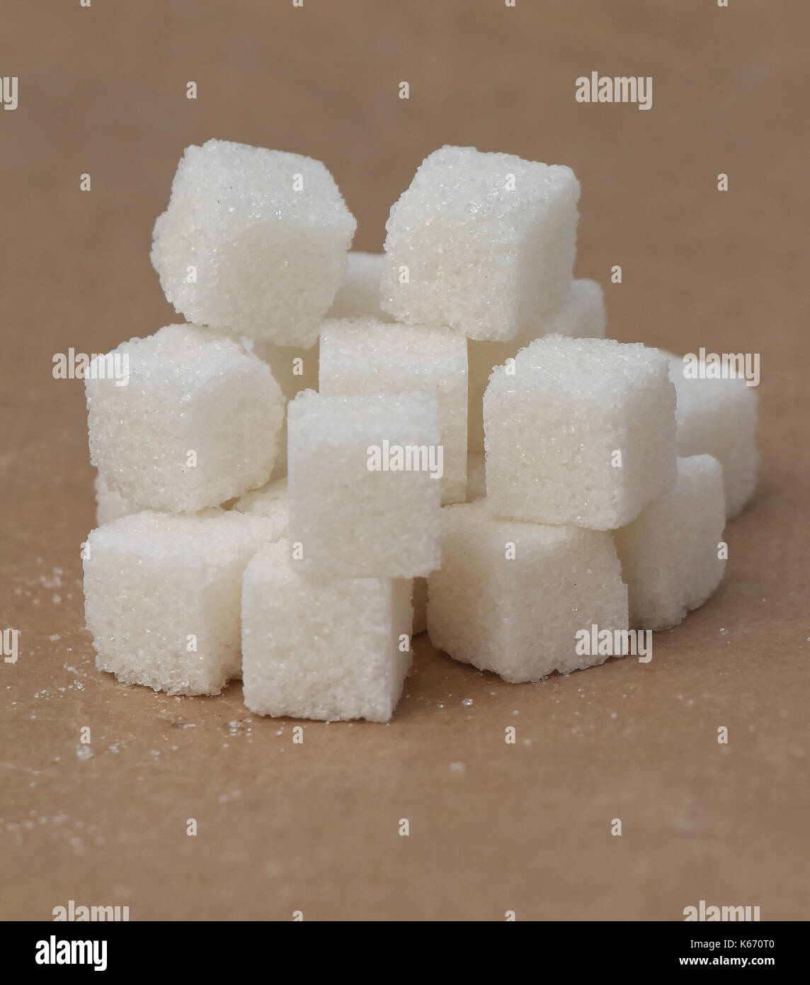 White sugar cubes pile on brown paper with small crumbs around bottom ...
