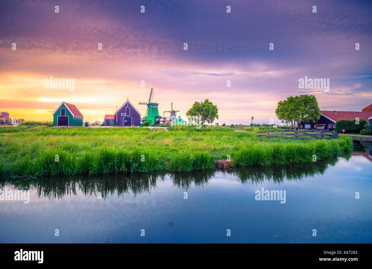 Traditional village with dutch windmills and river at sunset, Holland ...
