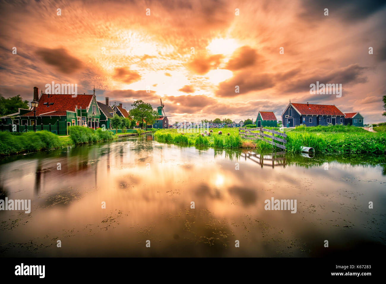 Traditional village with dutch windmills and river at sunset, Holland ...
