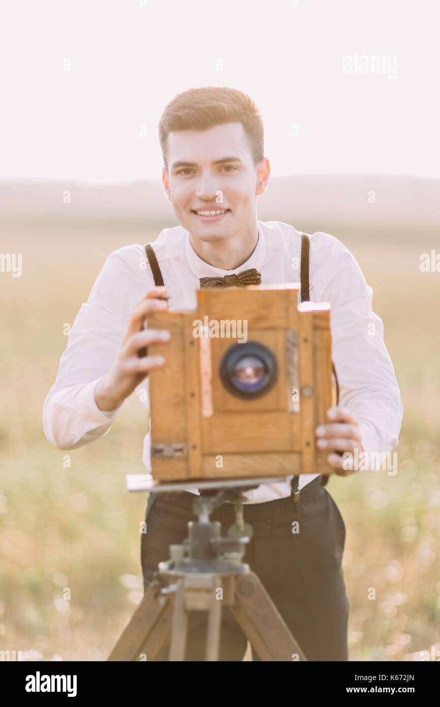 The close-up portrait of the vintage dressed groom taking photos using ...
