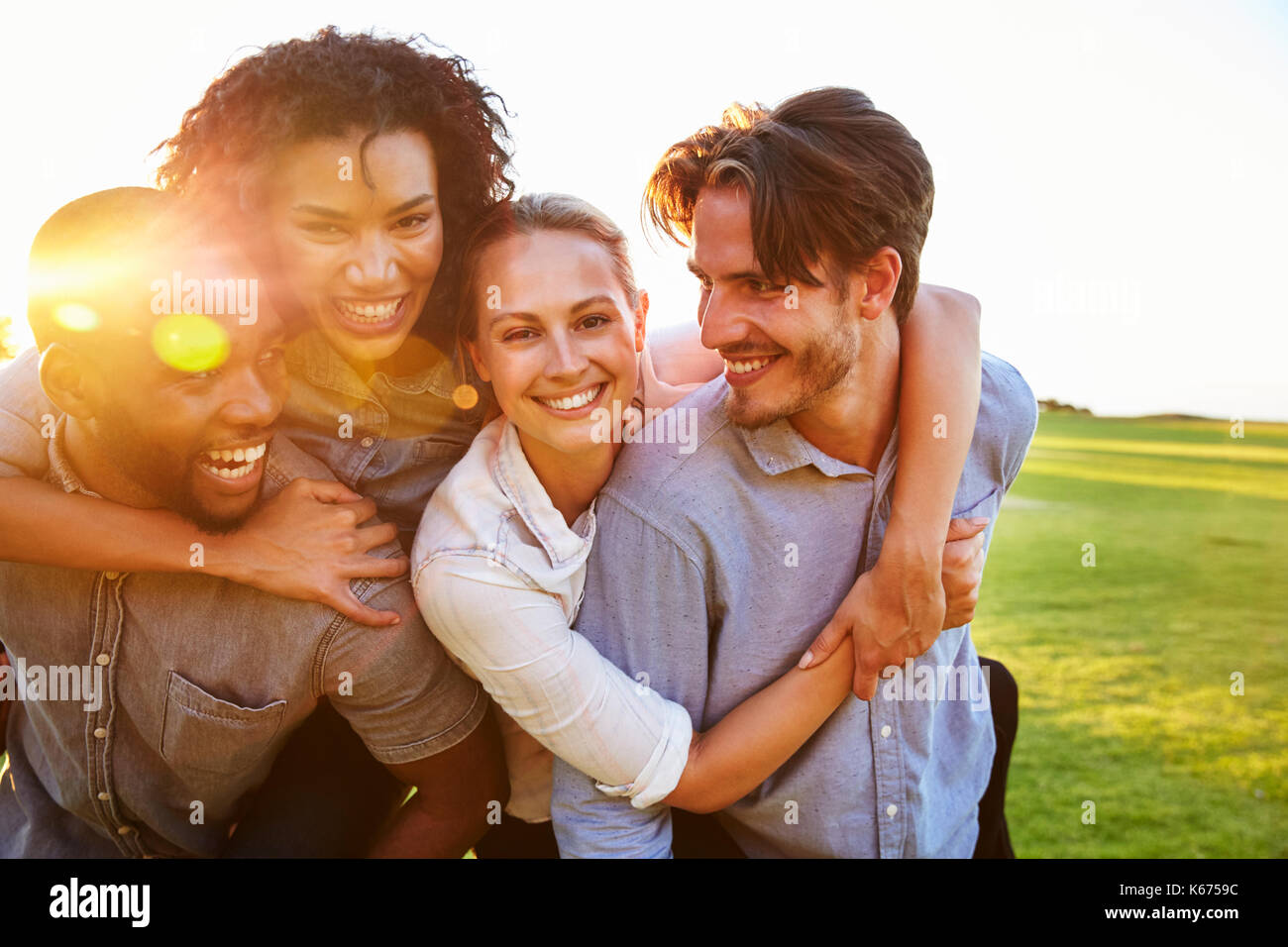 Two happy couples piggyback outdoors looking at each other Stock Photo ...
