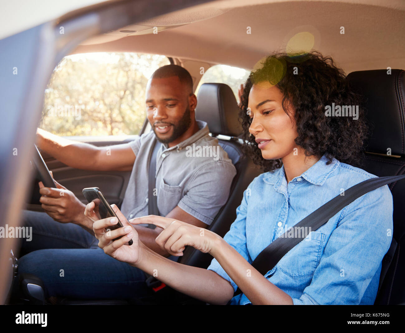 Young black couple navigating with smartphone on a road trip Stock ...