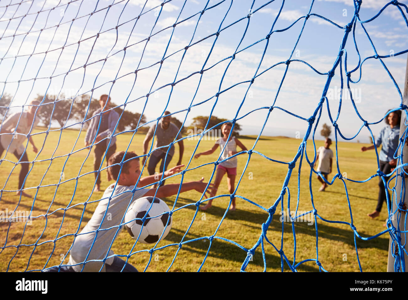 Two families playing football in park, scoring a goal Stock Photo - Alamy