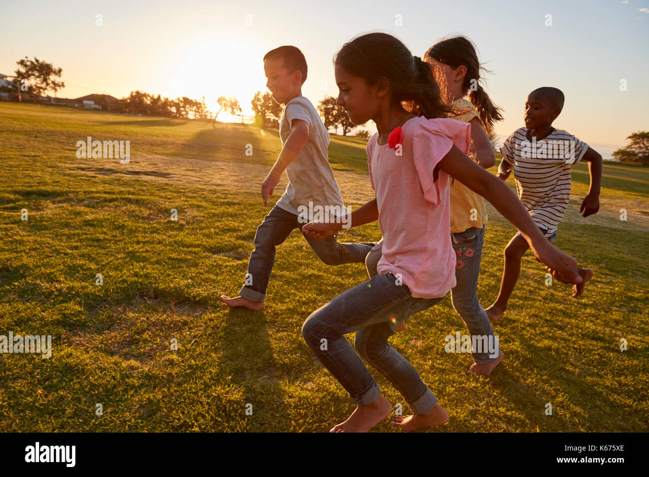 Four children running barefoot in a park Stock Photo - Alamy