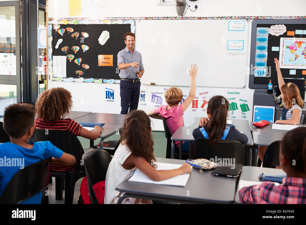 Happy pupils raising their hands class hi-res stock photography and ...