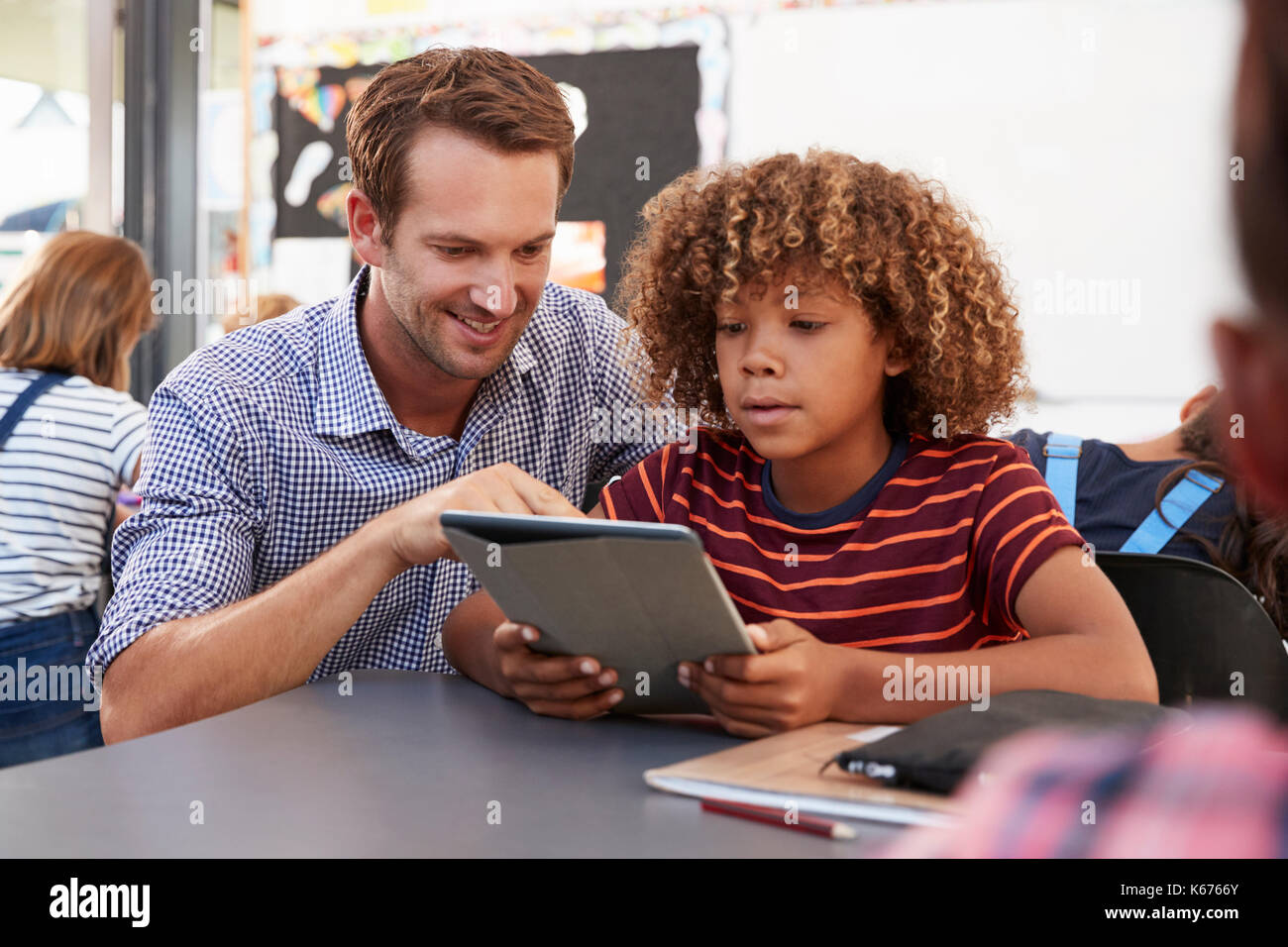 Teacher and schoolboy using tablet computer in class Stock Photo - Alamy