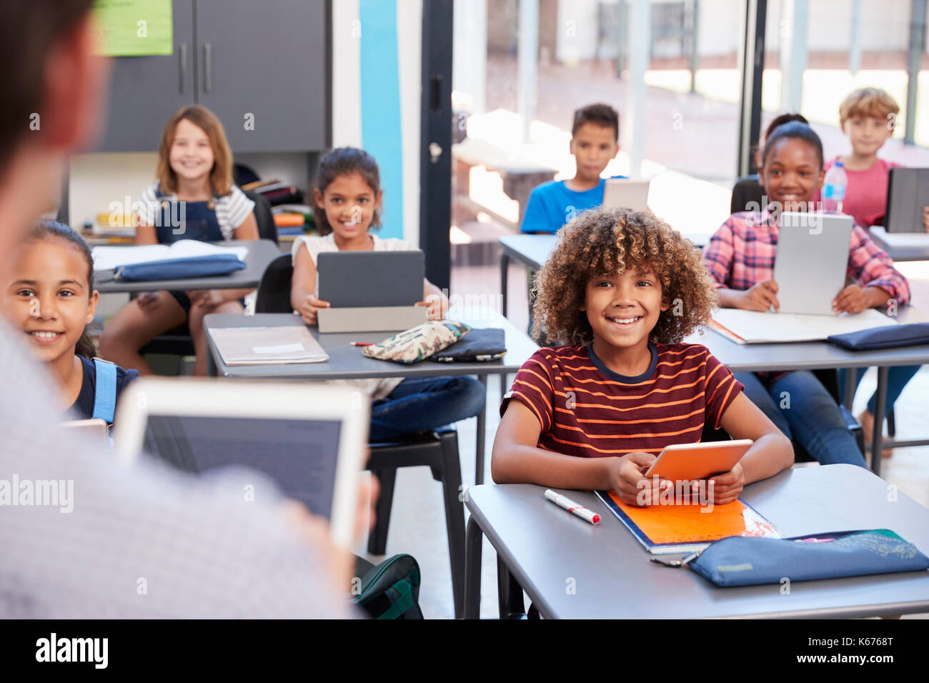 Elementary students looking at teacher, over shoulder view Stock Photo ...