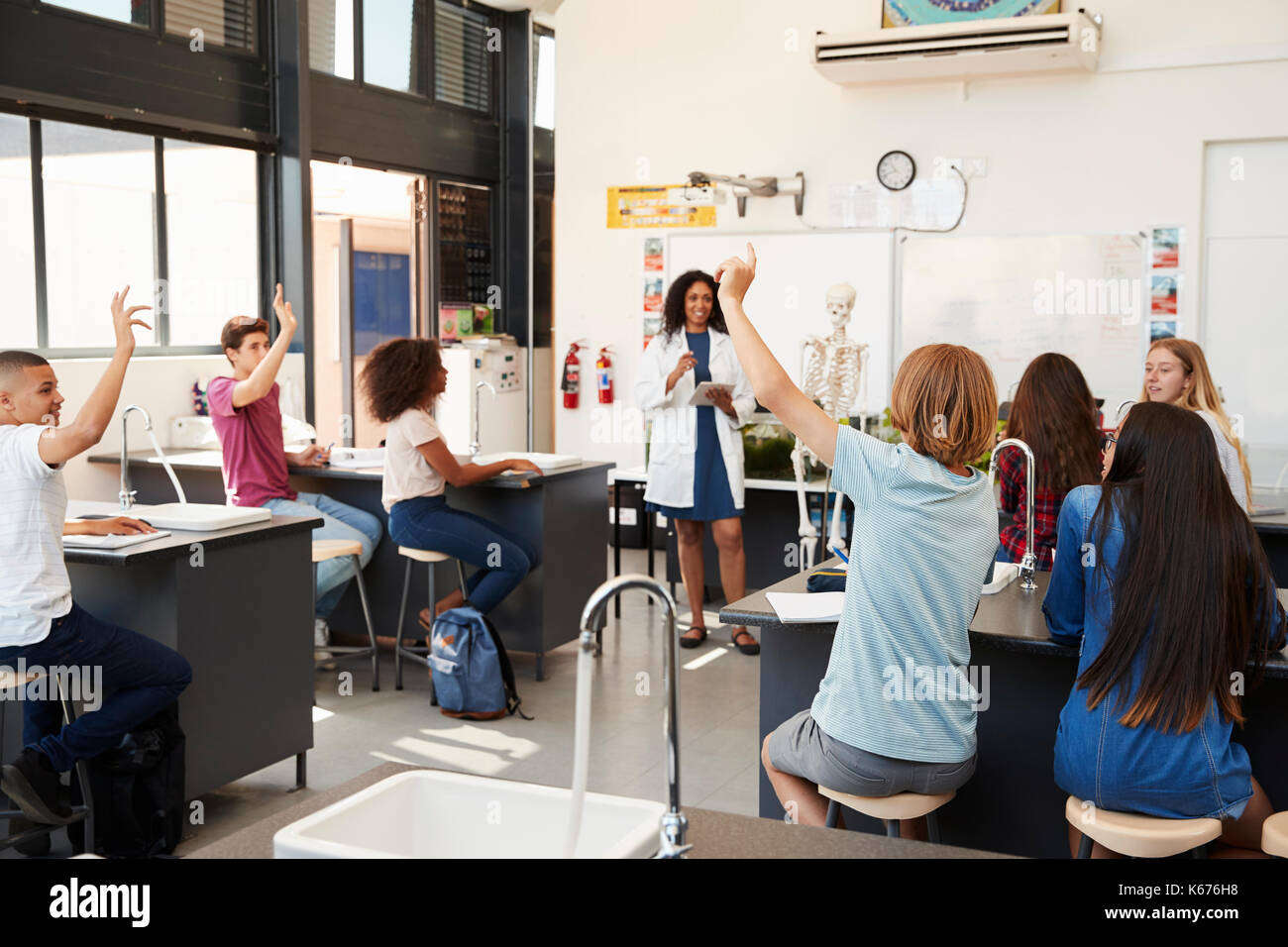 Pupils raising hands in a high school science lesson Stock Photo - Alamy