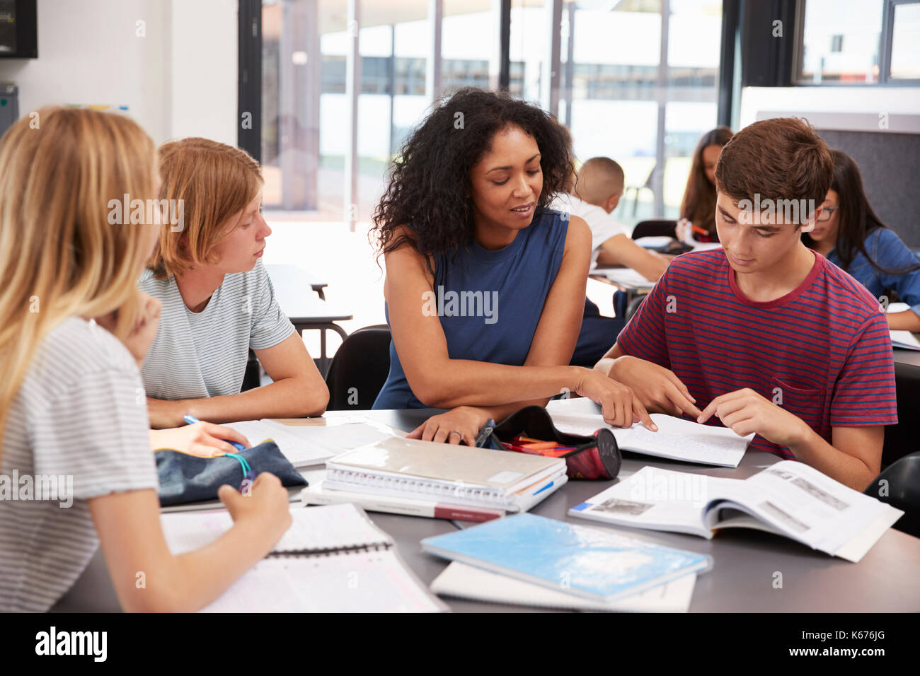 Teacher studying school books in class with high school kids Stock ...
