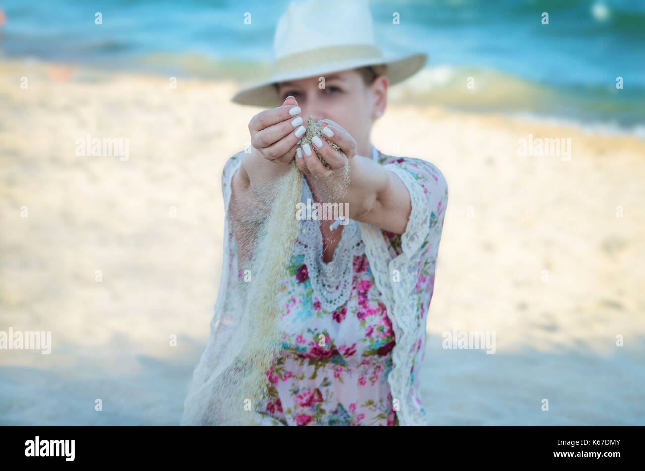 Woman standing on beach with sand running through her hands Stock Photo ...