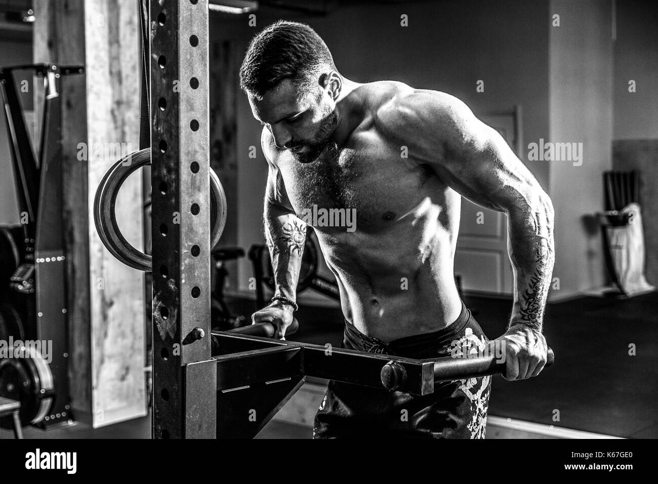 Strong muscular man doing push-ups on uneven bars in crossfit gym Stock ...