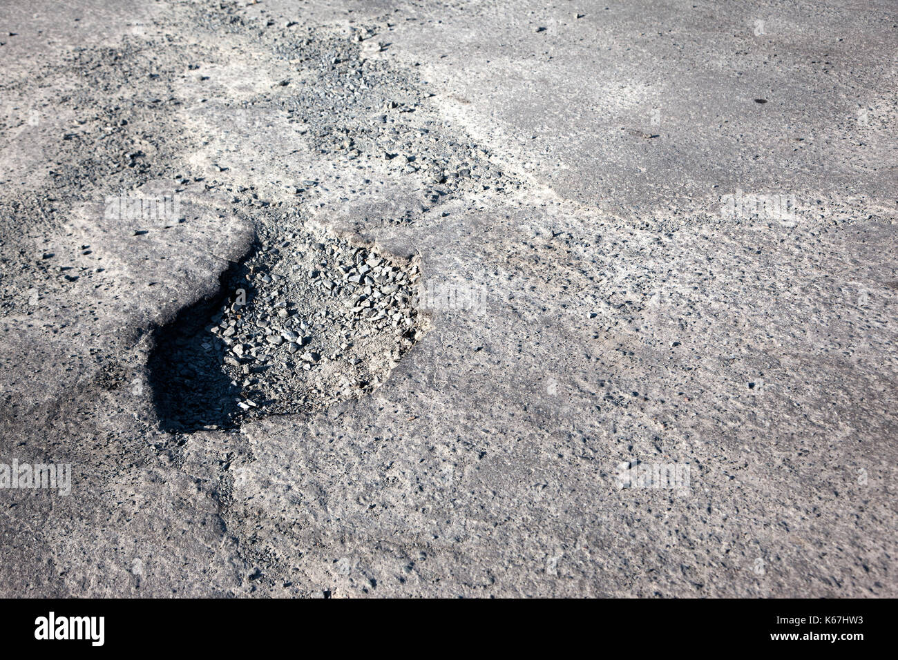 a deep pothole in a black and white paved road Stock Photo - Alamy
