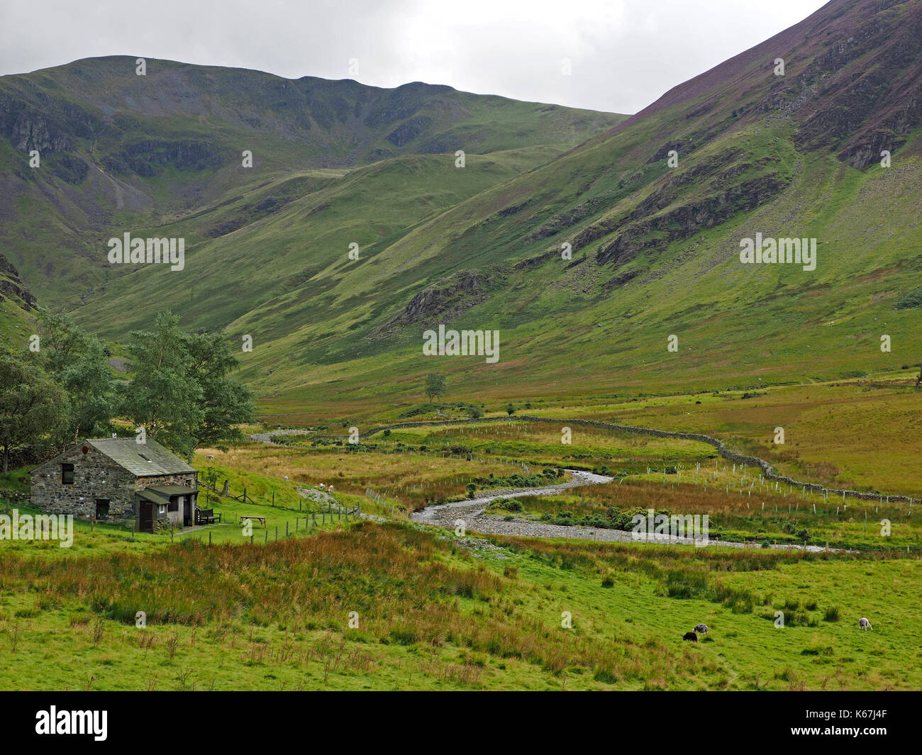slate building beside river winding down the Newlands Valley with ...