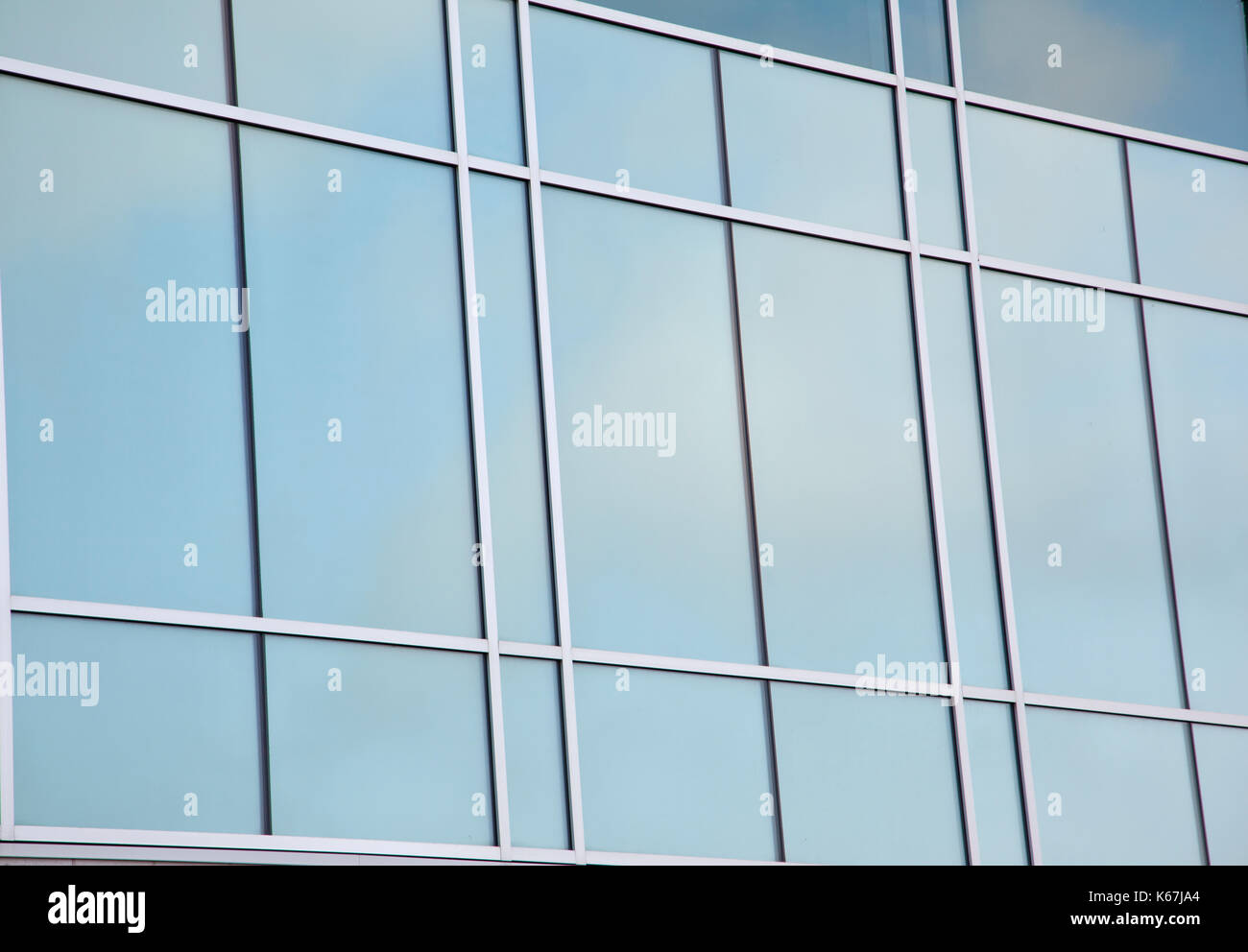 hint of sky and cloud reflected in glass windows at an office or ...