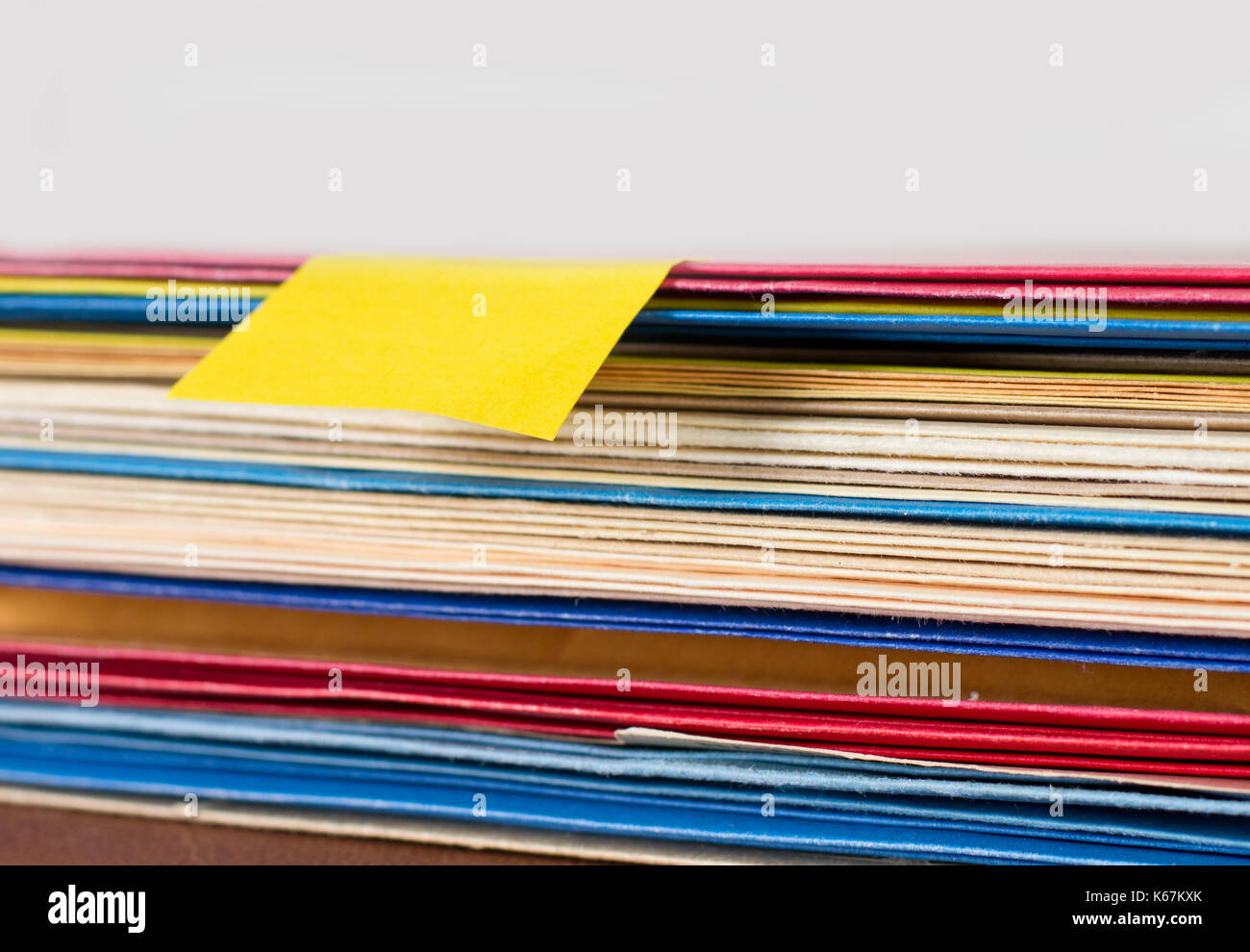a blank sticky note sits on a pile of colored work documents Stock ...