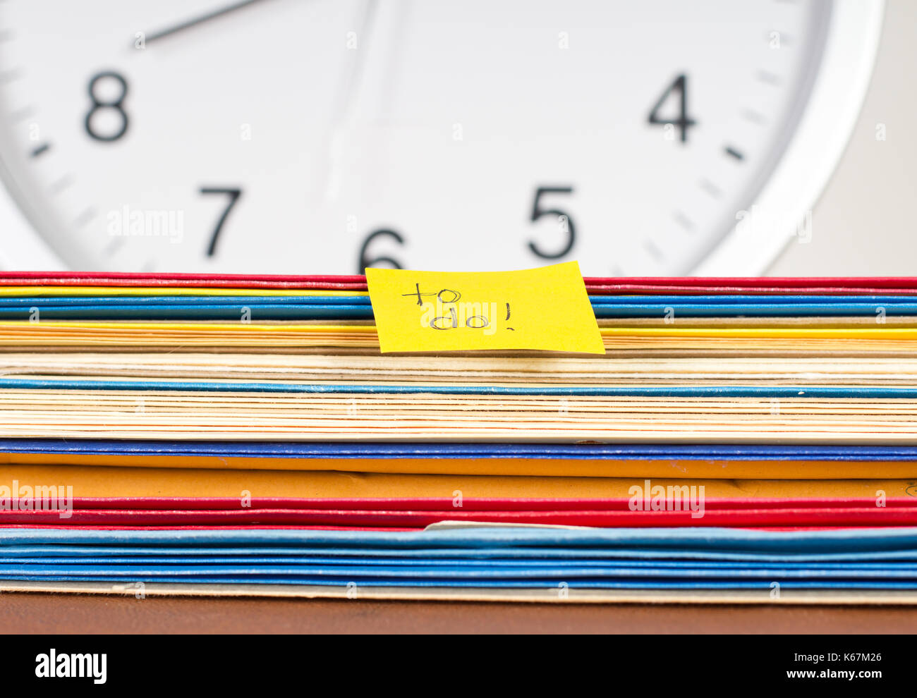 a stack of work papers with a clock and to do note signify a deadline ...
