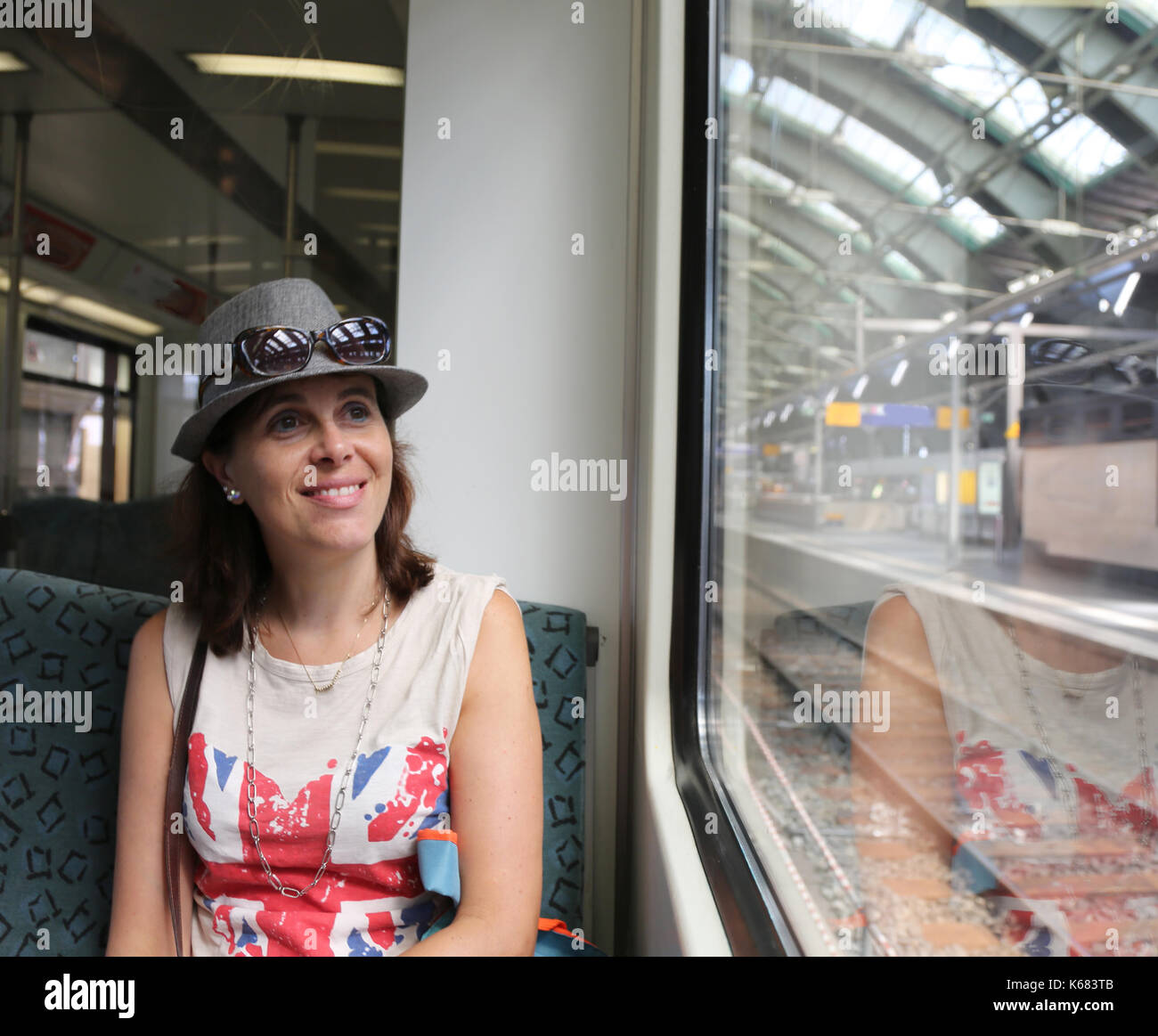 pretty woman with hat sitting in train in the station before leaving ...