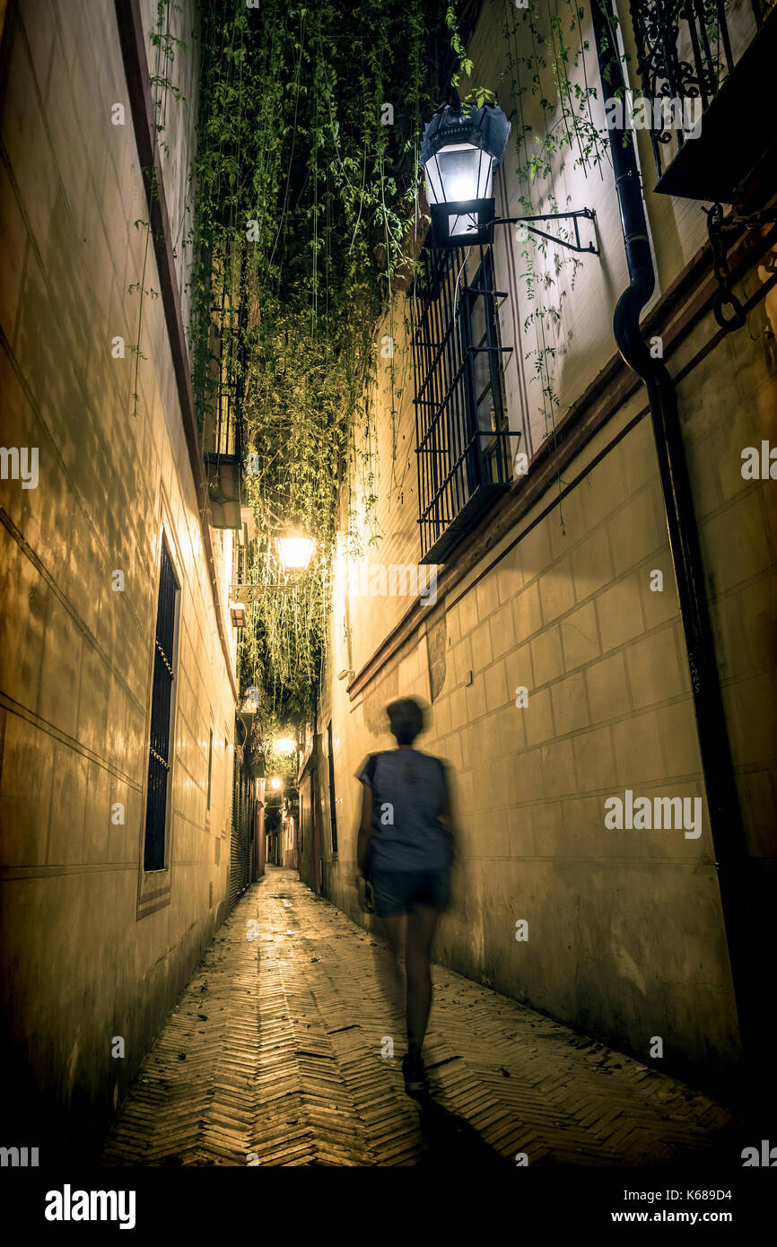 Tourist walk by narrow street of night typical in Seville, Andalusia ...