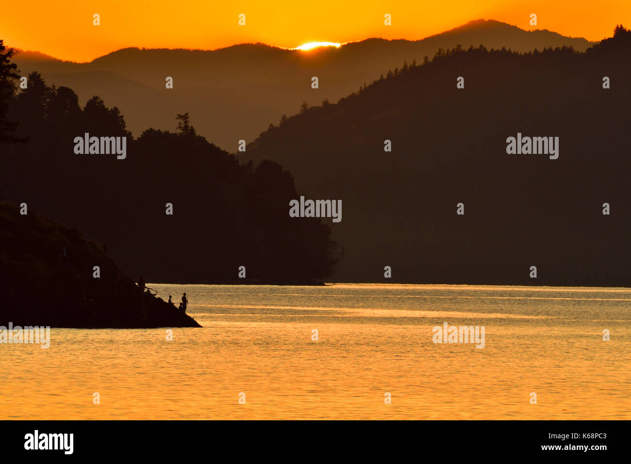 A beautiful sunset as the sun sinks below the mountain ridge line at ...